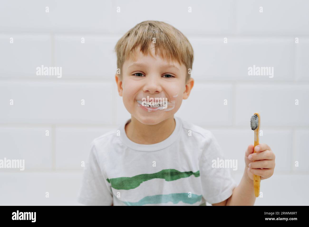 cute 5 years old boy brushing teeth with bamboo tooth brush in bathroom ...