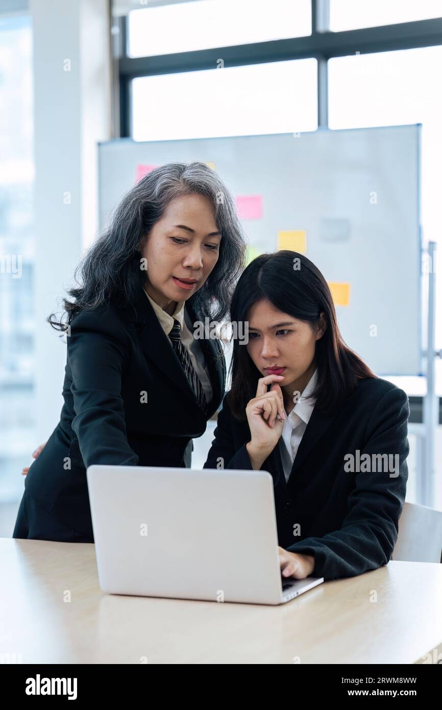 Two diverse financial assistant working on laptop while senior ...