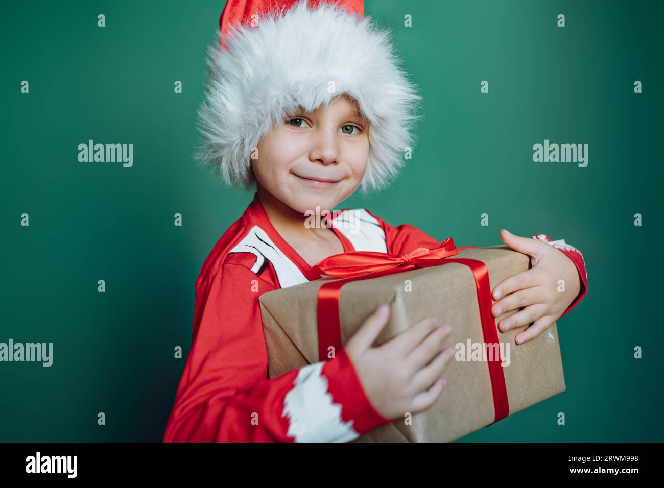 happy smiling caucasian boy in santa tee shirt and hat holding a box ...
