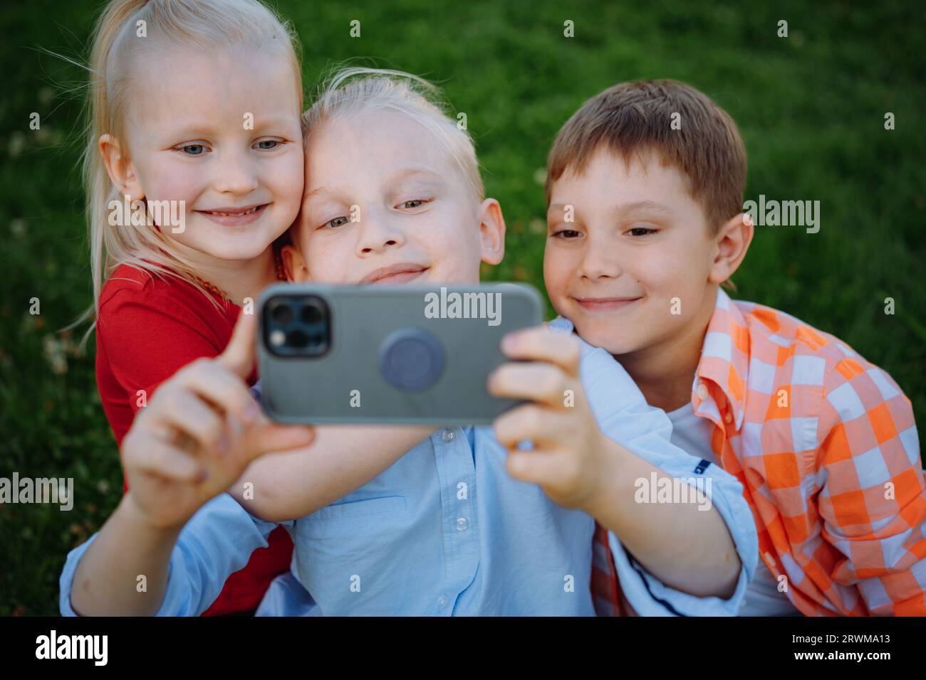 cute funny children shooting selfie with smartphone. Kids in park ...