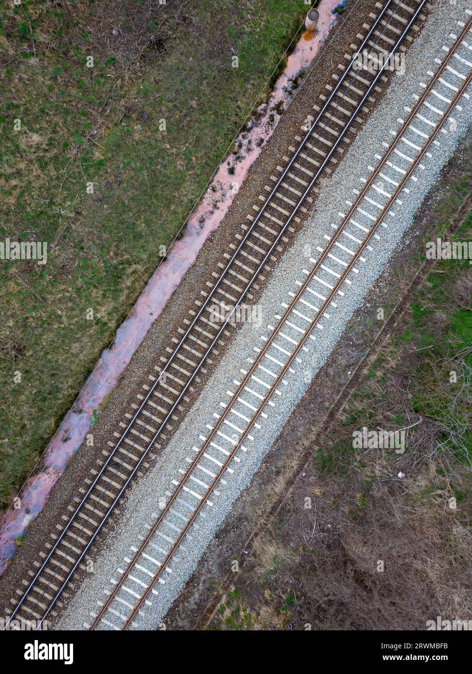An aerial view of a set of railroad tracks cutting through a lush green ...