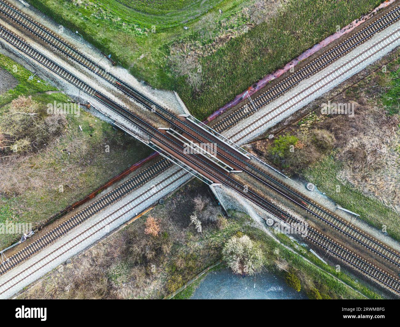 An aerial view of a set of railroad tracks cutting through a lush green ...