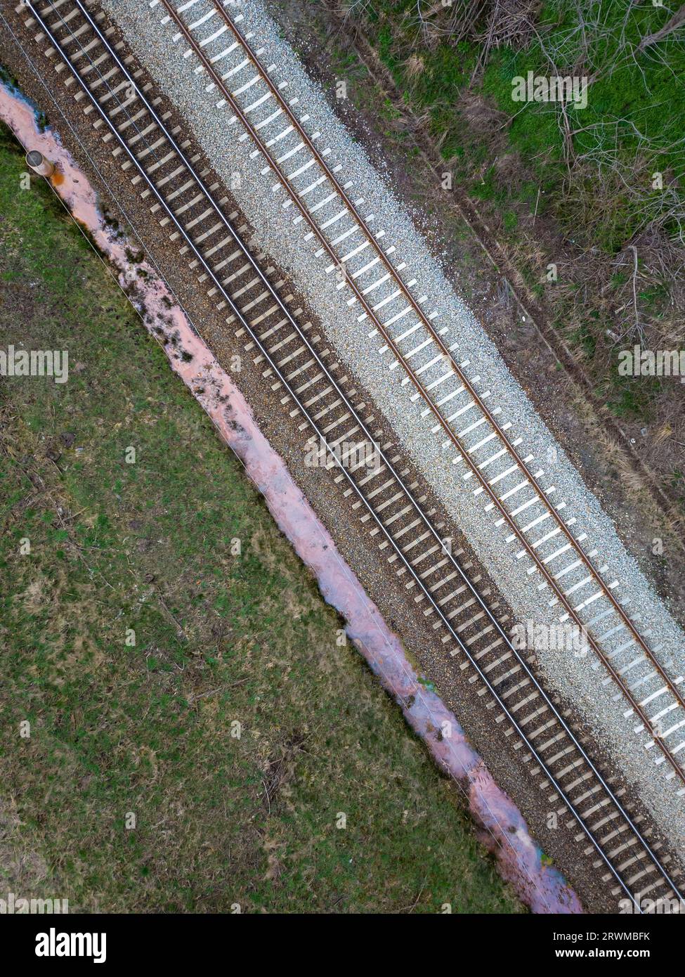 An aerial view of a set of railroad tracks cutting through a lush green ...