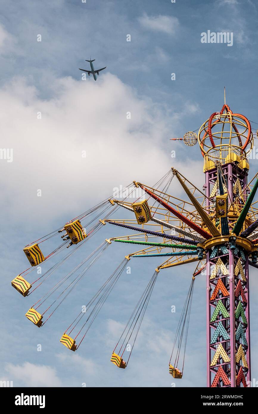A low angle of an airplane flying above a Ferris wheel Stock Photo - Alamy
