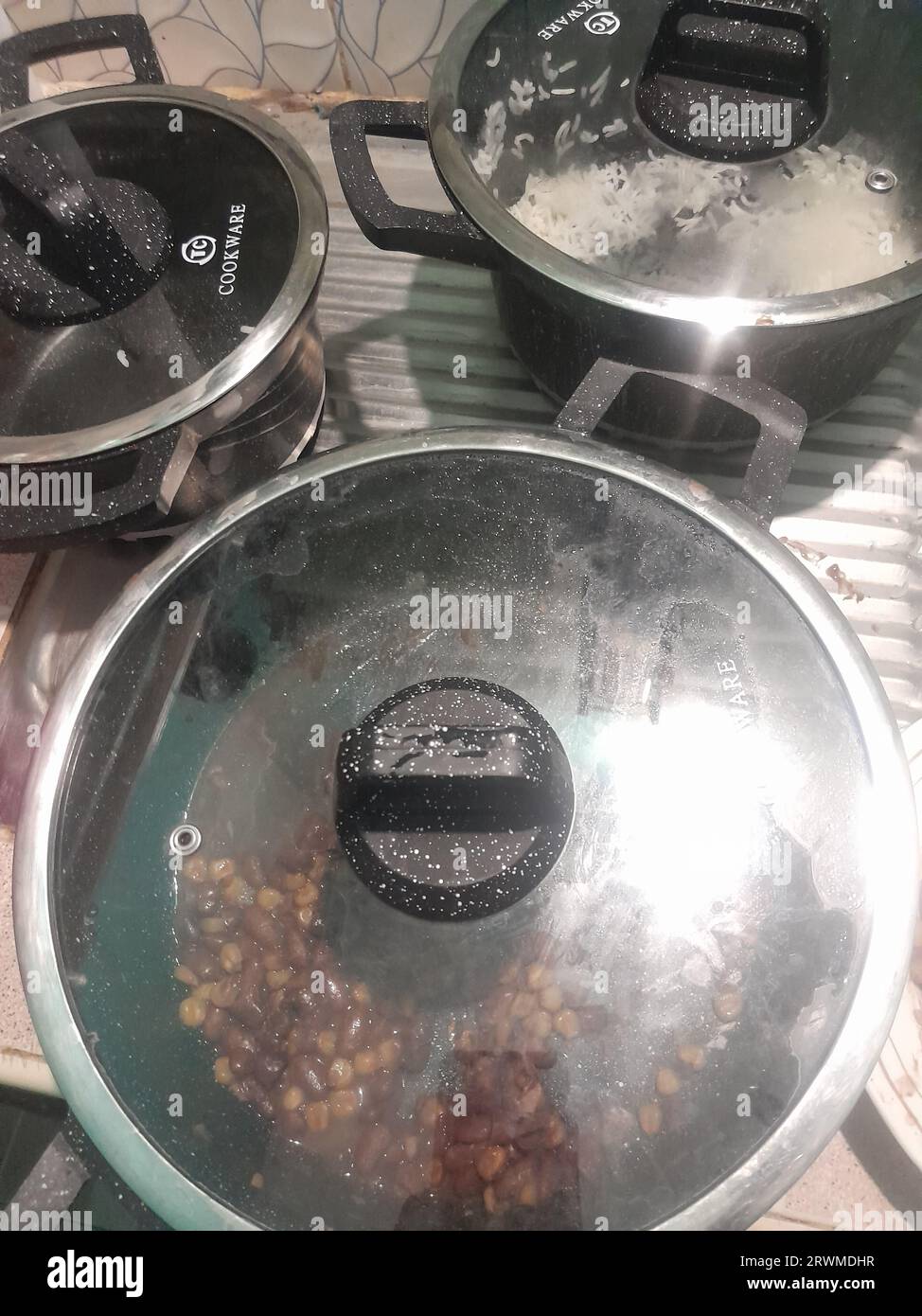 Three stainless steel cooking pots on a black kitchen stove top Stock ...
