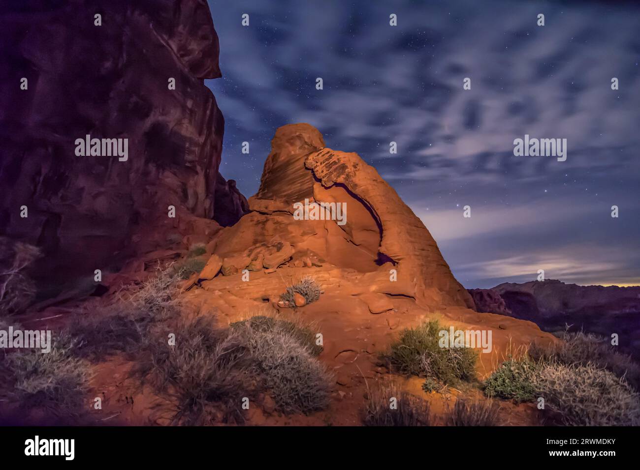 A rugged mountain landscape illuminated by a full moon against a ...