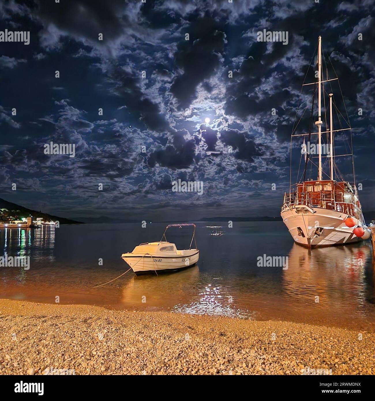 The boats moored in shallow water near a shoreline illuminated by the ...