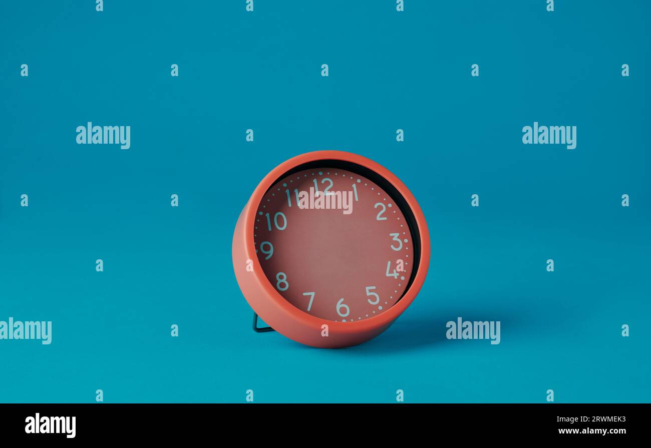 a pink clock without hour or minute hands on a blue background with ...