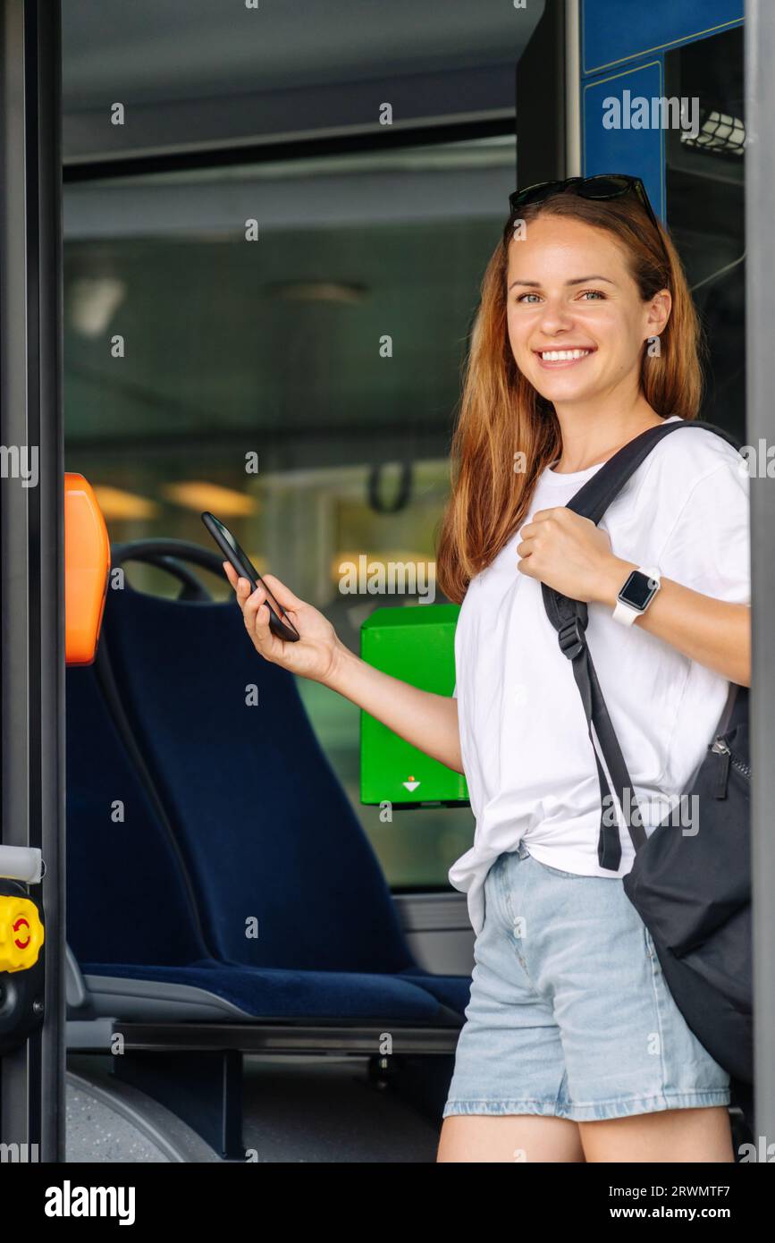 Happy young woman using qr code of free pass for shuttle bus in city ...
