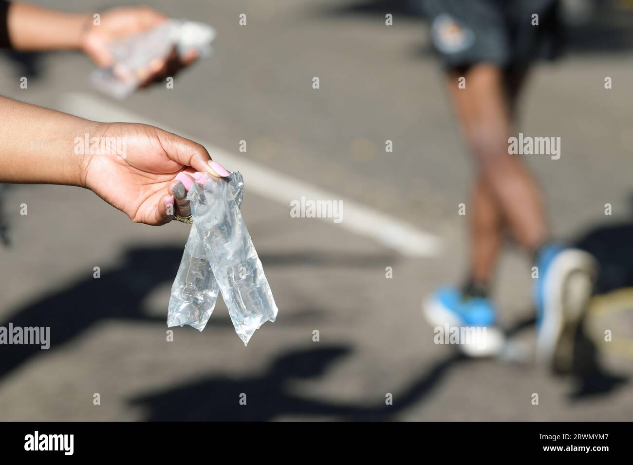 Human hand holding plastic packaging, water at refreshment station ...