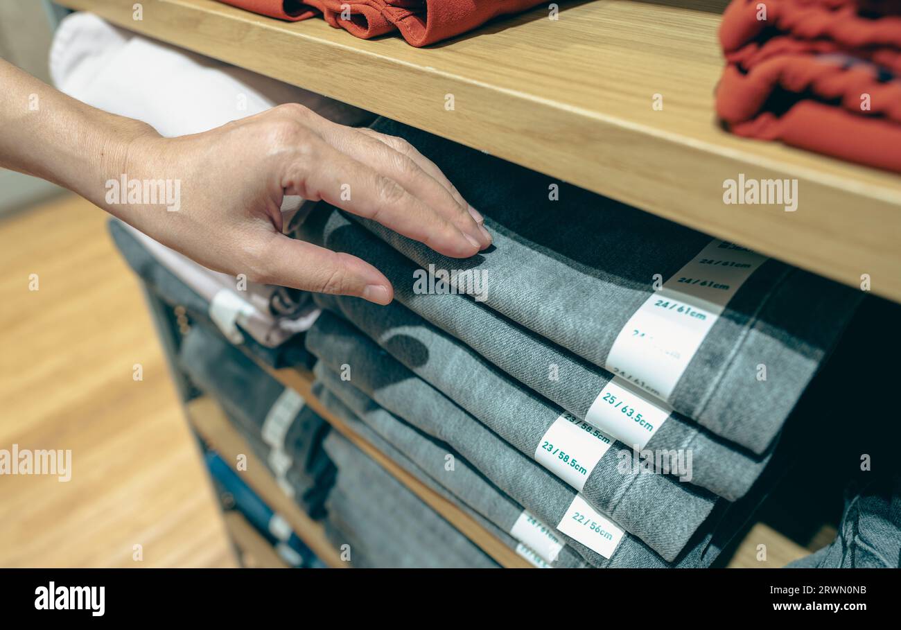 Woman shopping jeans in clothing store. Woman choosing clothes. Jeans ...