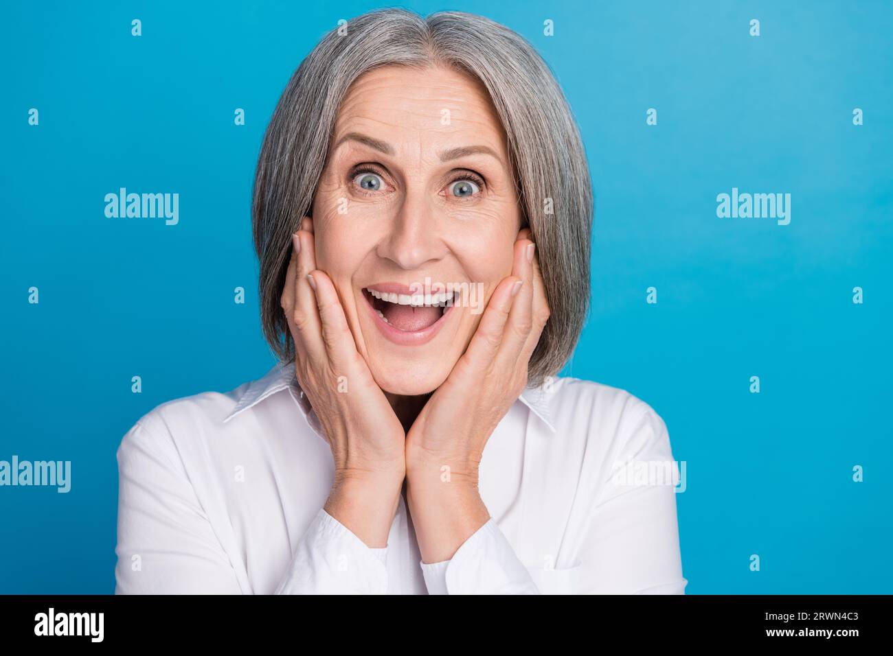 Photo of astonished cheerful aged lady arms touch cheekbones open mouth ...