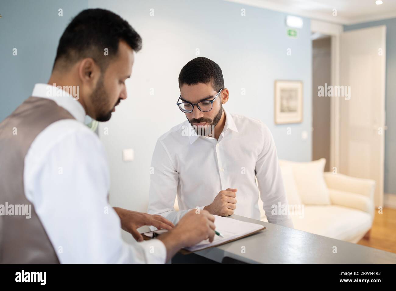 Arabic Businessman Checking In At Hotel, Signing Papers With ...