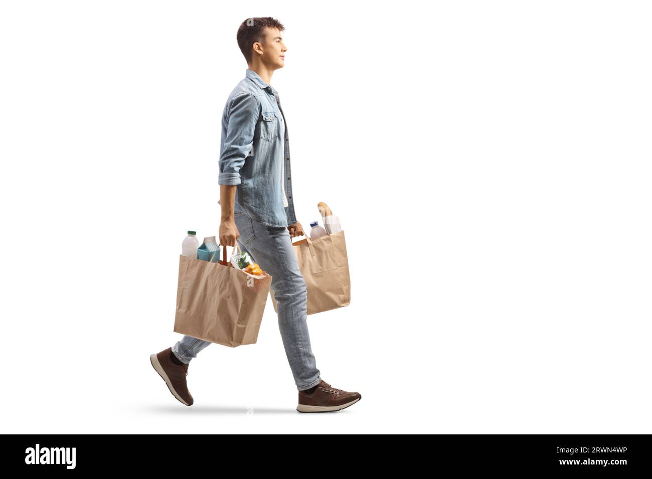 Full length profile shot of a male teenager carrying grocery bags ...
