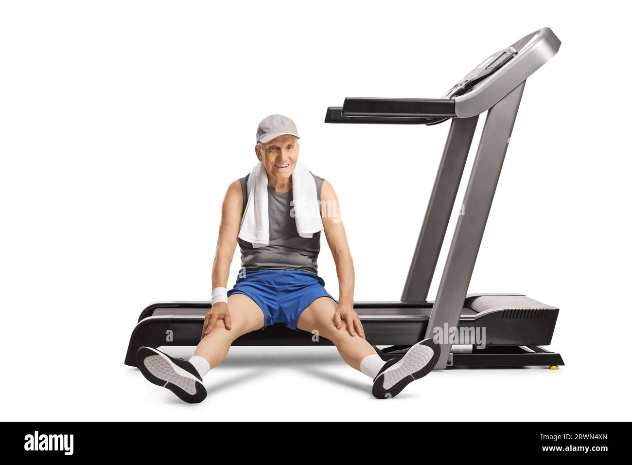Tired elderly man sitting on a treadmill isolated on white background ...