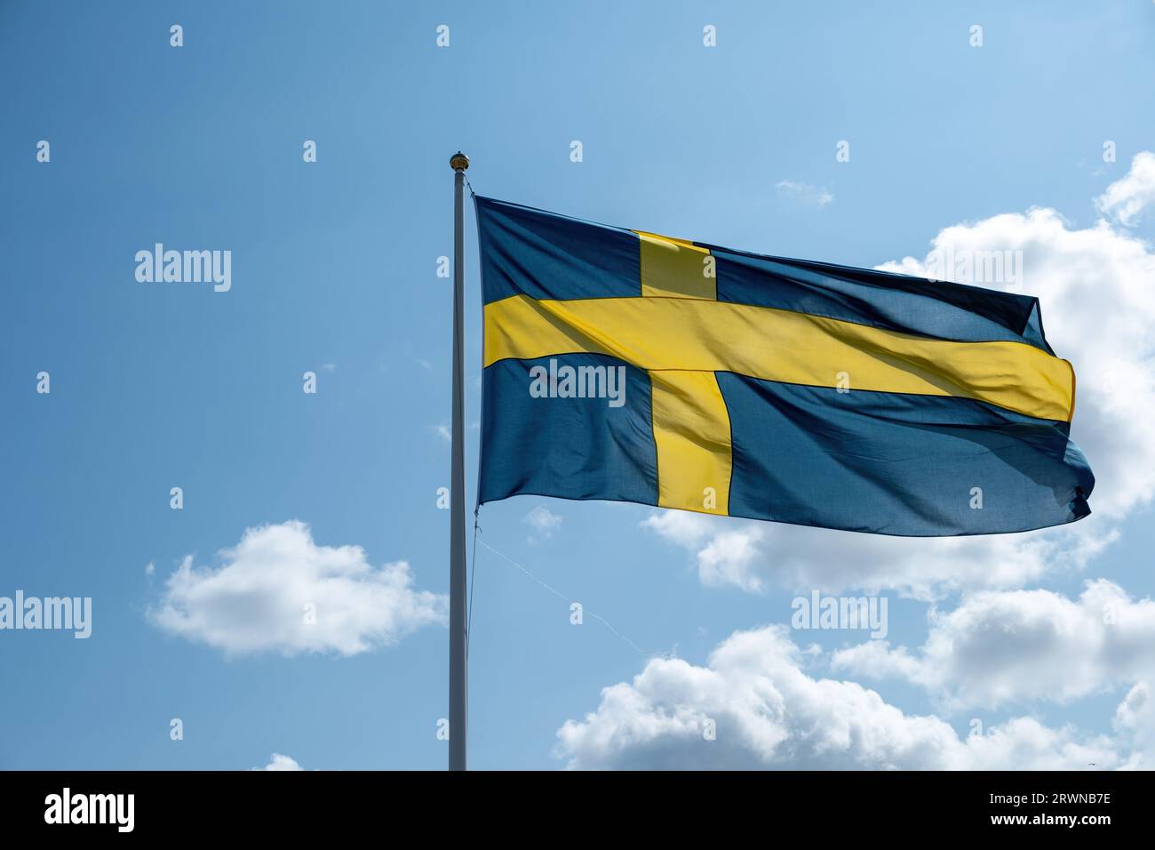 Sweden national flag waving on a flagpole, blue cloudy sky background ...