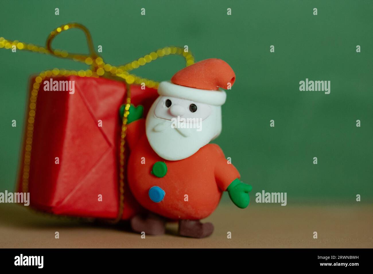 Toy miniature plasticine jolly Santa Claus with a red gift box ...