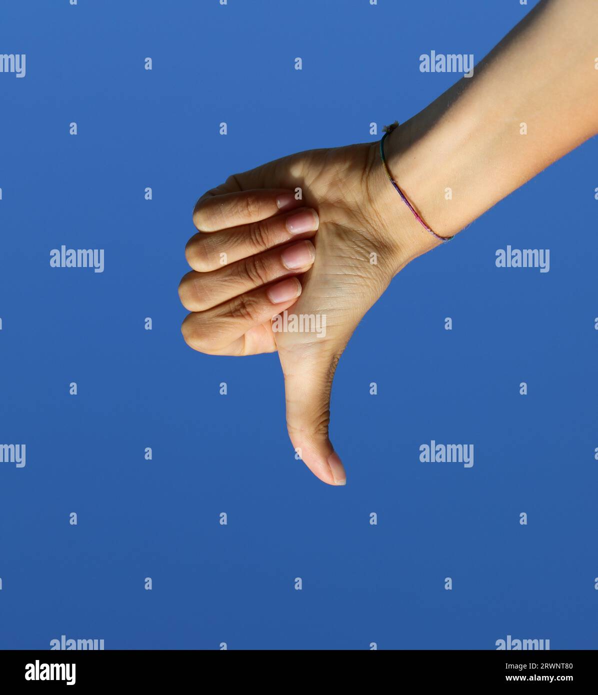 hand of girl with thumb down meaning denial or failure and blue sky ...