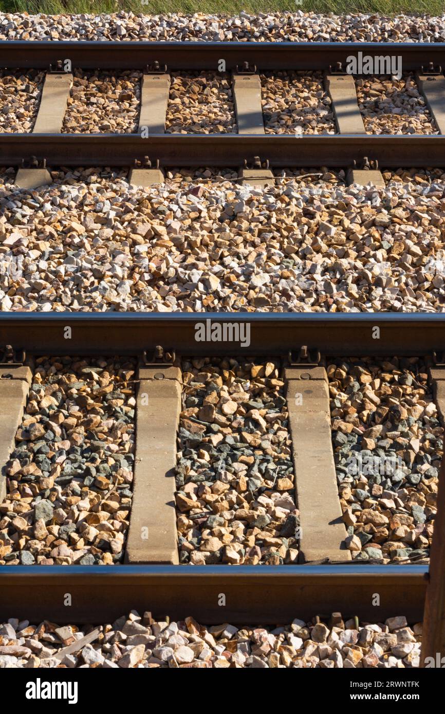 Train tracks and crossbars between stones and gravel, from the side ...