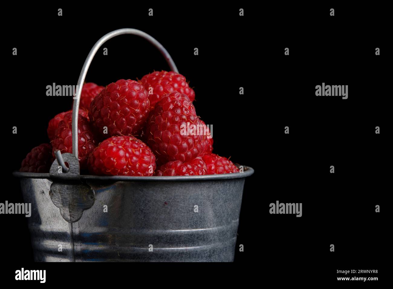 Bucket filled with raspberries, black background Stock Photo - Alamy
