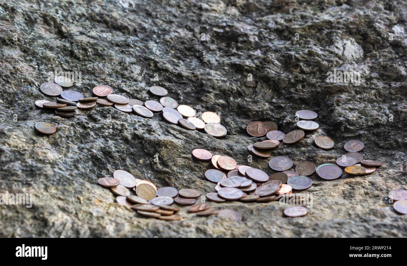 Small coins on a stone. Ritual for being rich Stock Photo - Alamy