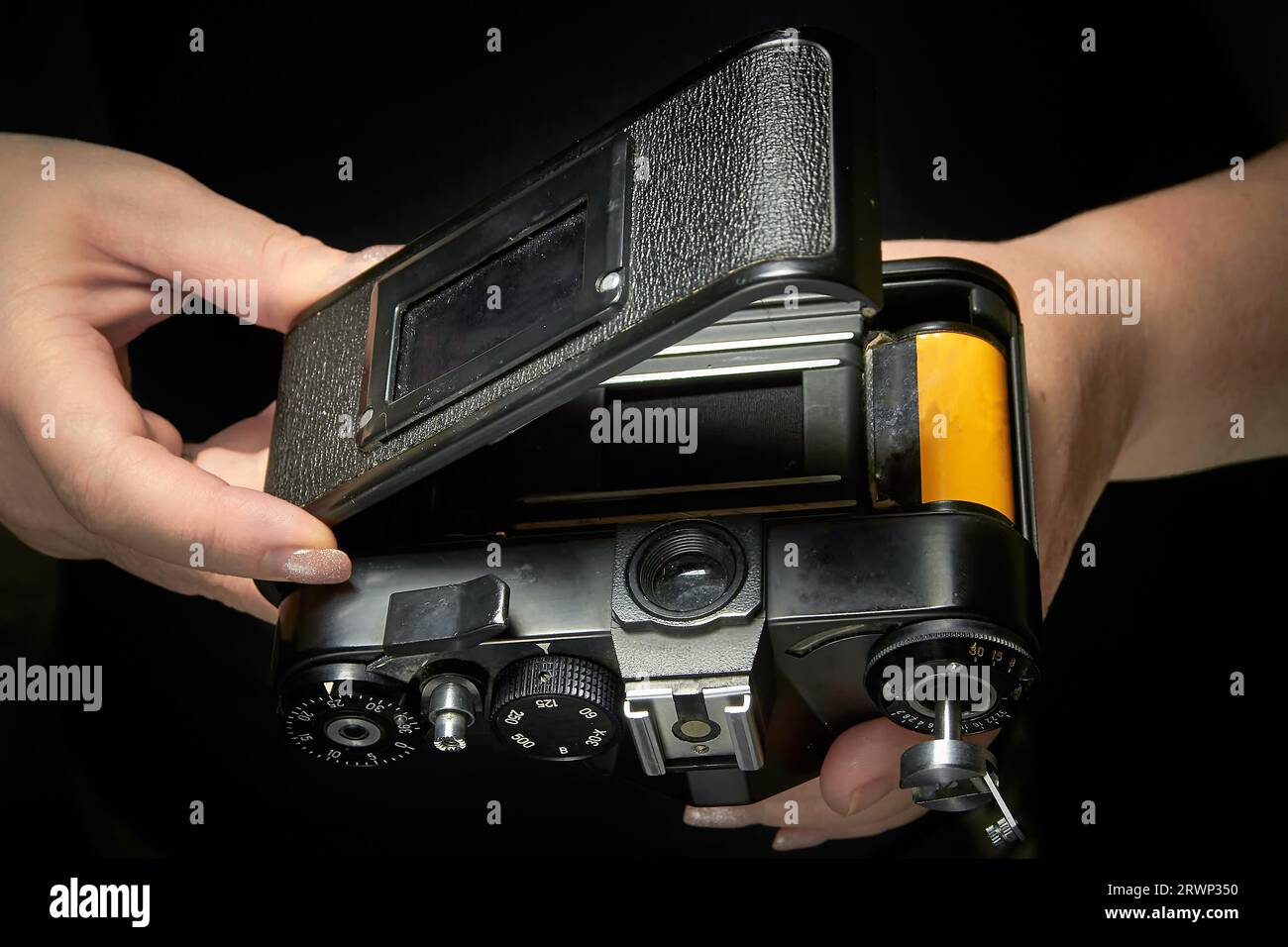 A girl opened the lid of an antique film camera to replace a roll of ...