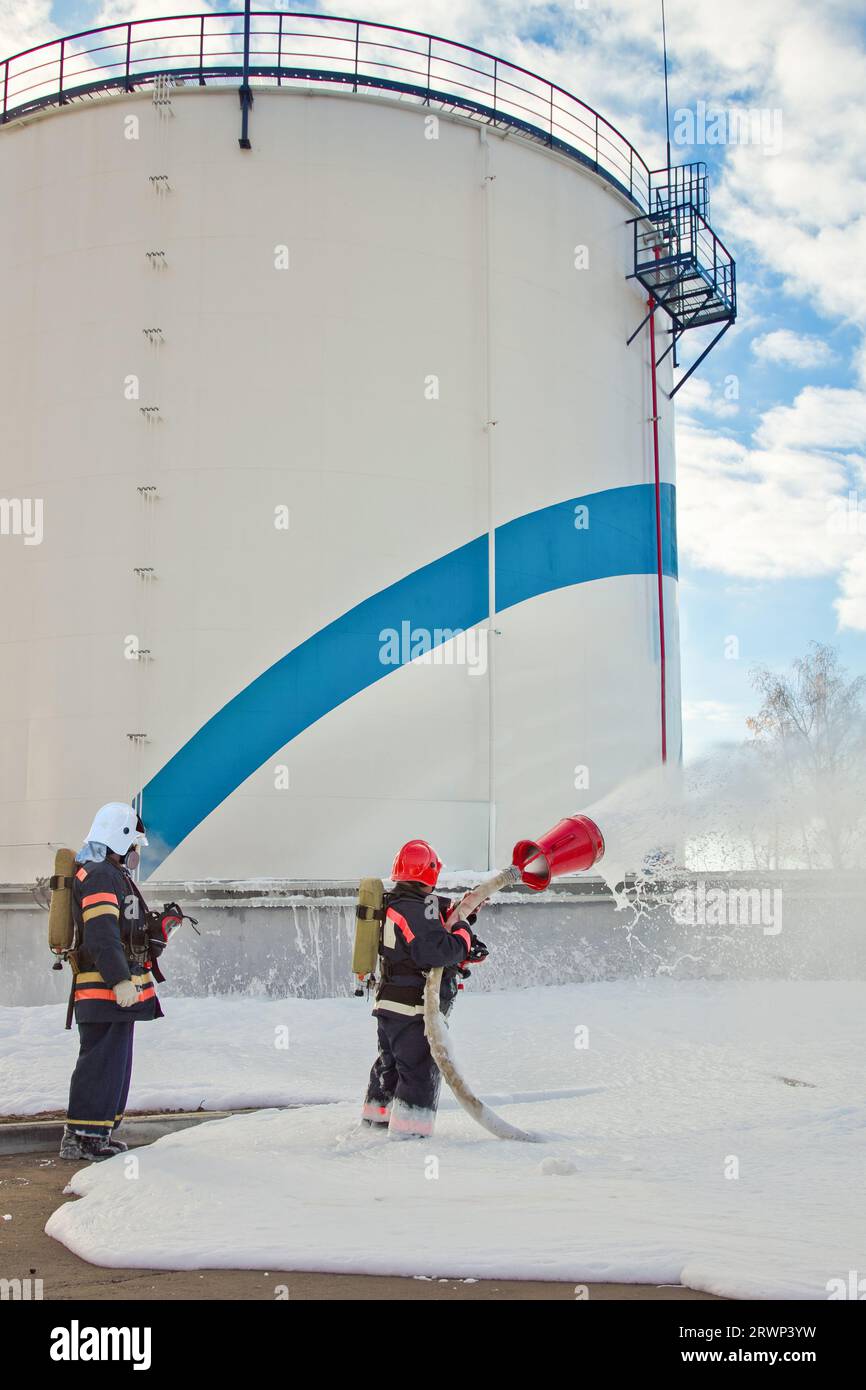 Firemen extinguish fire at oil tanks by foam spraying hose Stock Photo ...