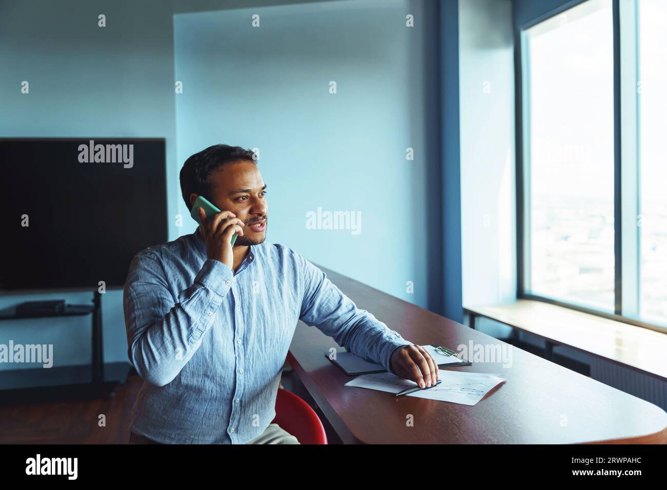 Focused businessman is talking phone with client while sitting in ...