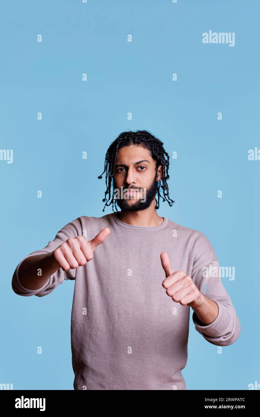 Cool arab man showing two thumbs up gesture and looking at camera with ...
