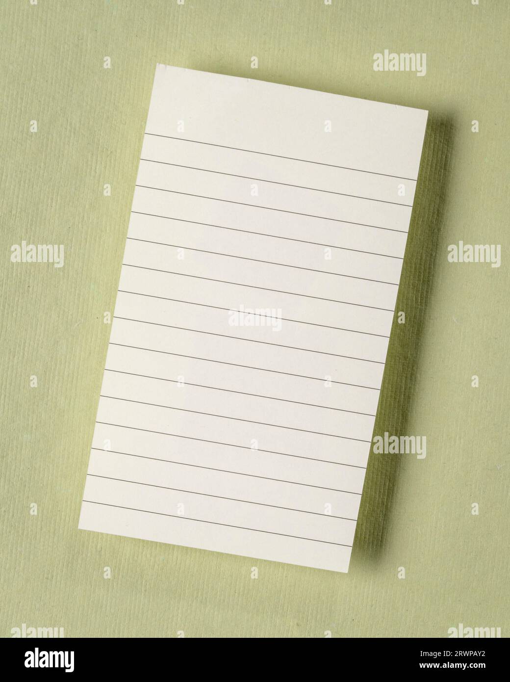 small blank sheet of ruled paper against green textured background ...