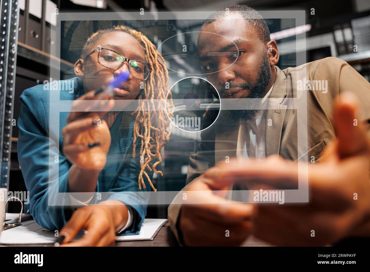 Young detectives checking hologram in incident room, examining ...