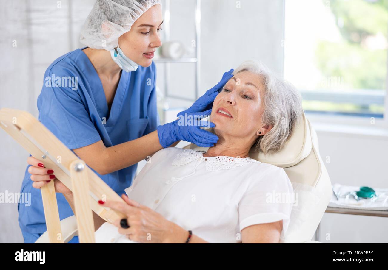 Mature patient with mirror, doctor with gloves Stock Photo - Alamy