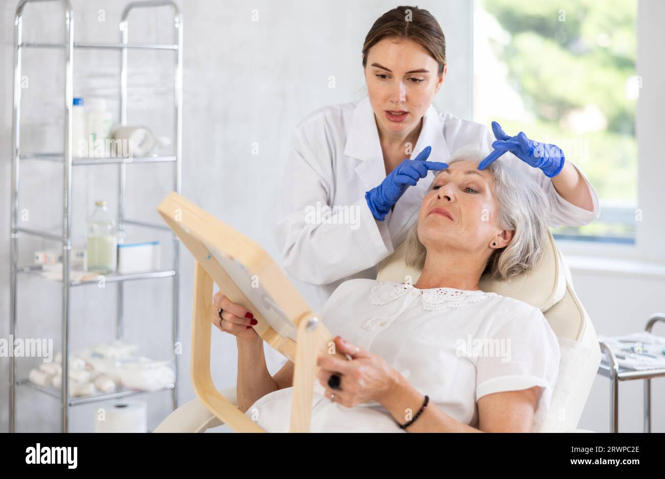 Elderly patient looking in mirror at clinic Stock Photo - Alamy