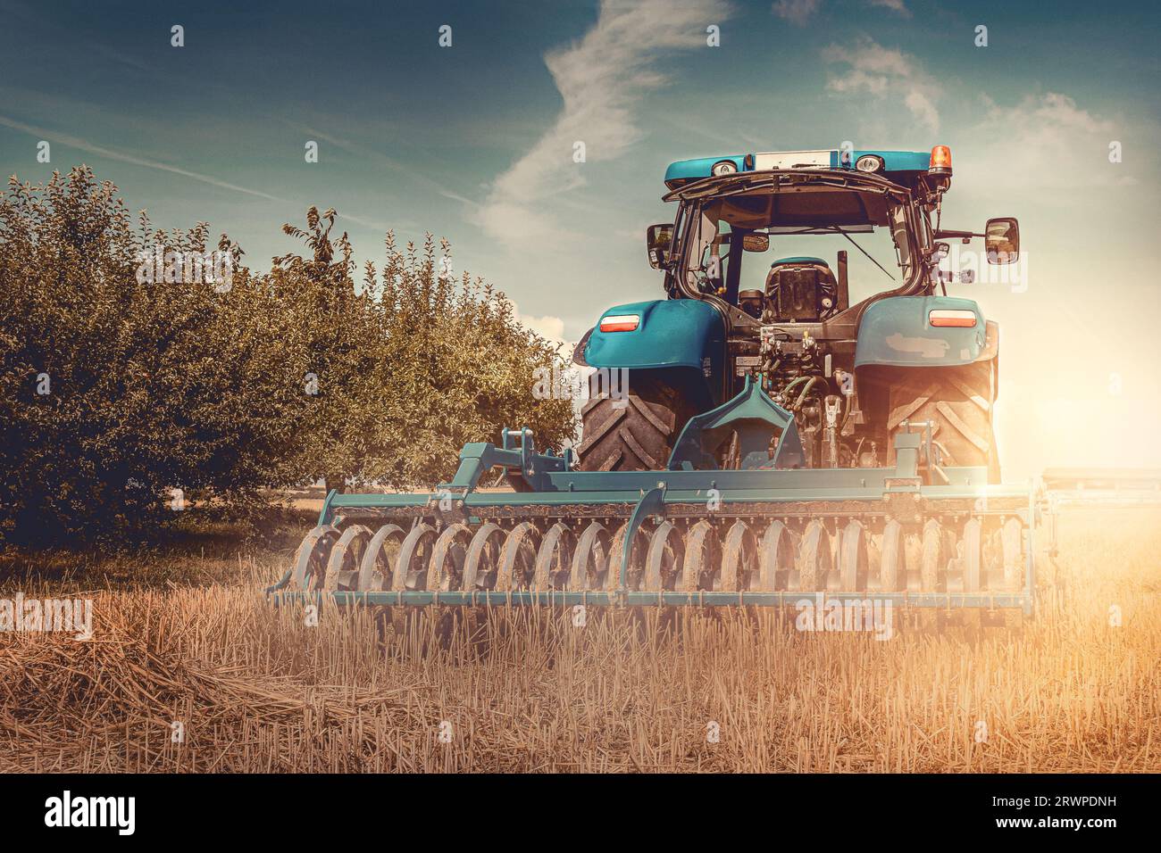 Tractor of a farmer in the pasture of the farm mowing with sunshine and ...