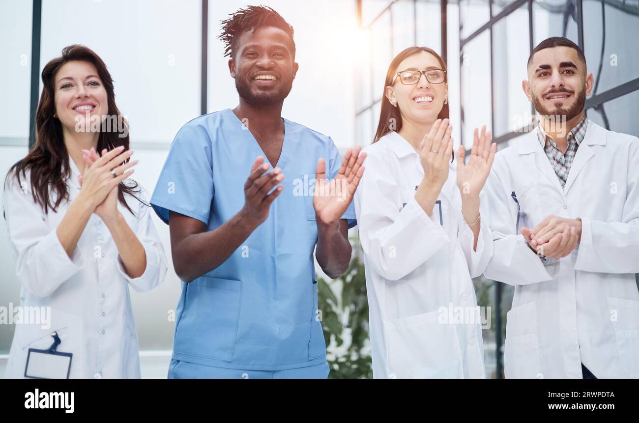 Successful team of different doctors clapping hands Stock Photo - Alamy