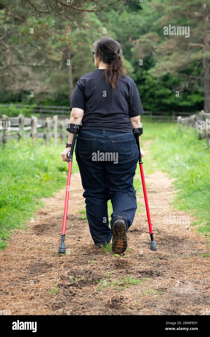 A disabled woman with forearm crutches walking along a path Stock Photo ...