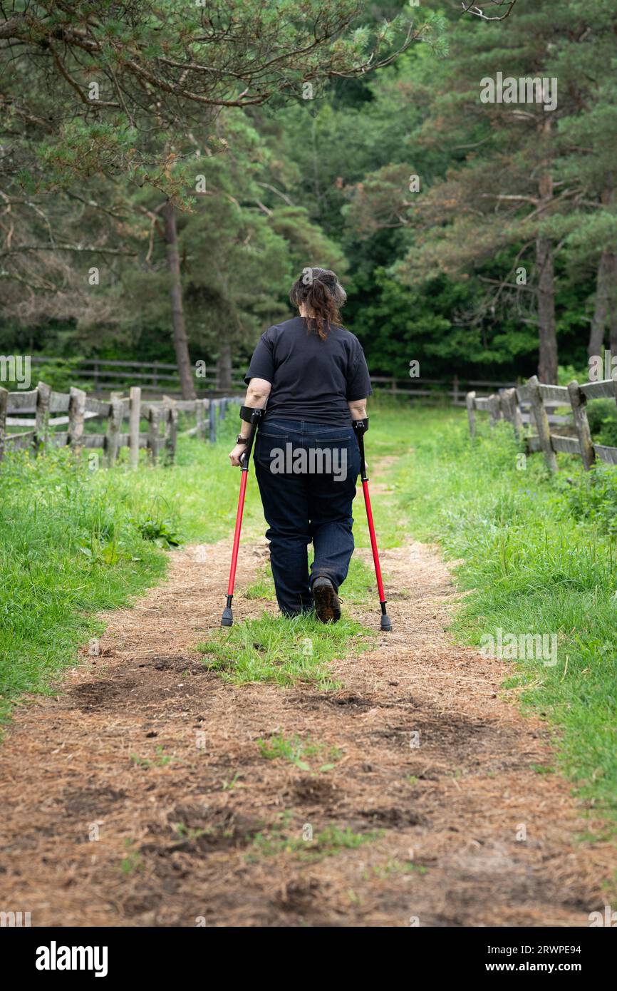 A disabled woman with forearm crutches walking along a path Stock Photo ...