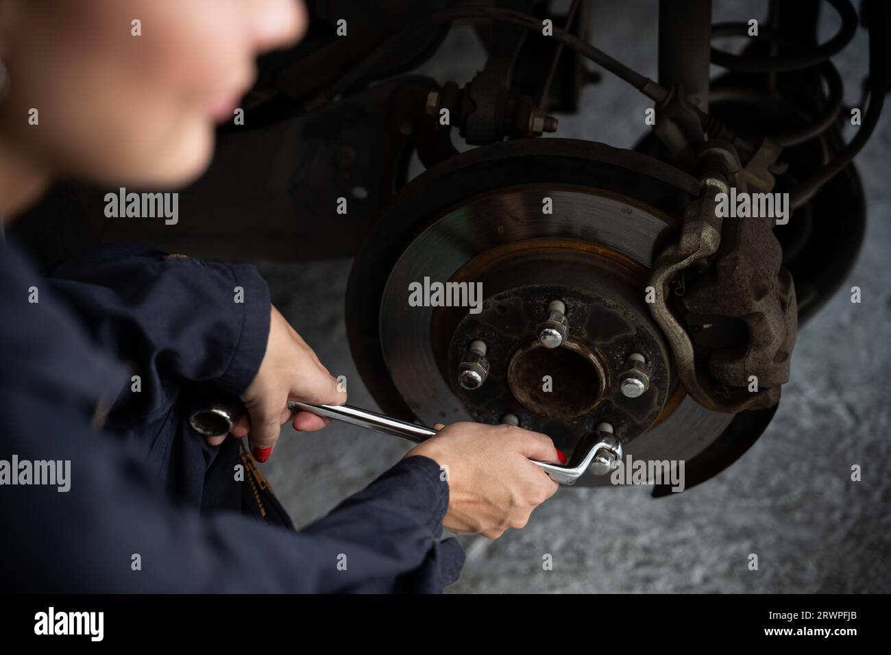 Hardworking female mechanic changing car wheel in auto repair workshop. Automotive service ...