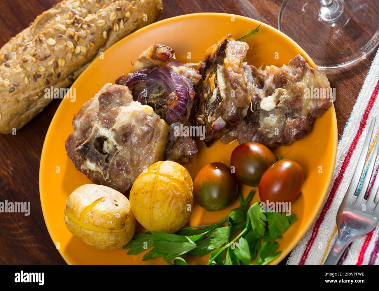 Lamb leg chops with baked potatoes, tomatoes and greens Stock Photo - Alamy