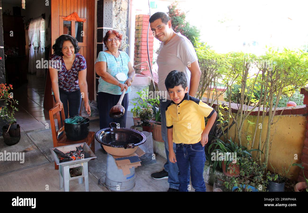 Family of mom, dad, grandmother and son cook outdoors in the patio of a ...
