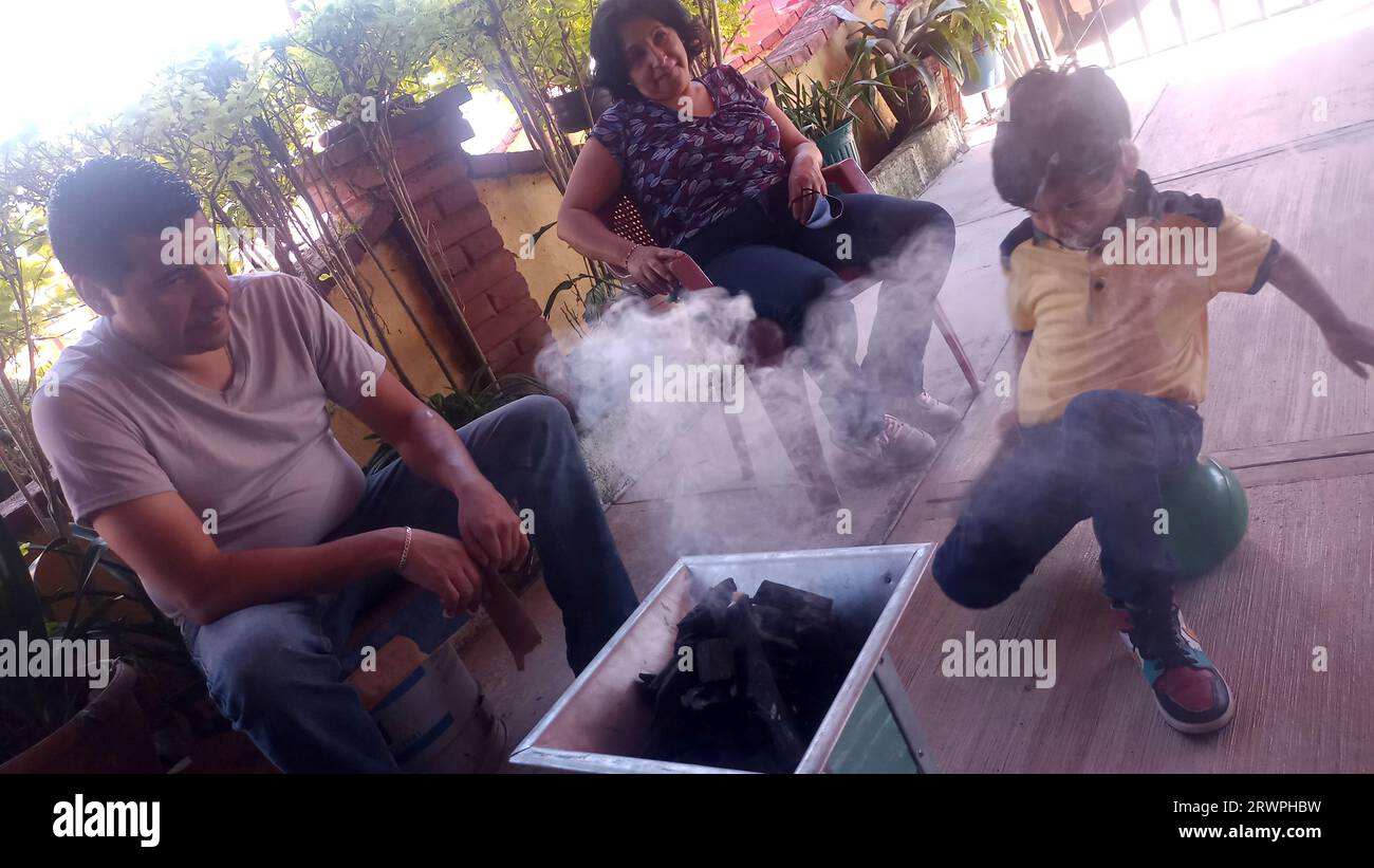 Family of mom, dad and son cook outdoors in the patio of a poor house ...