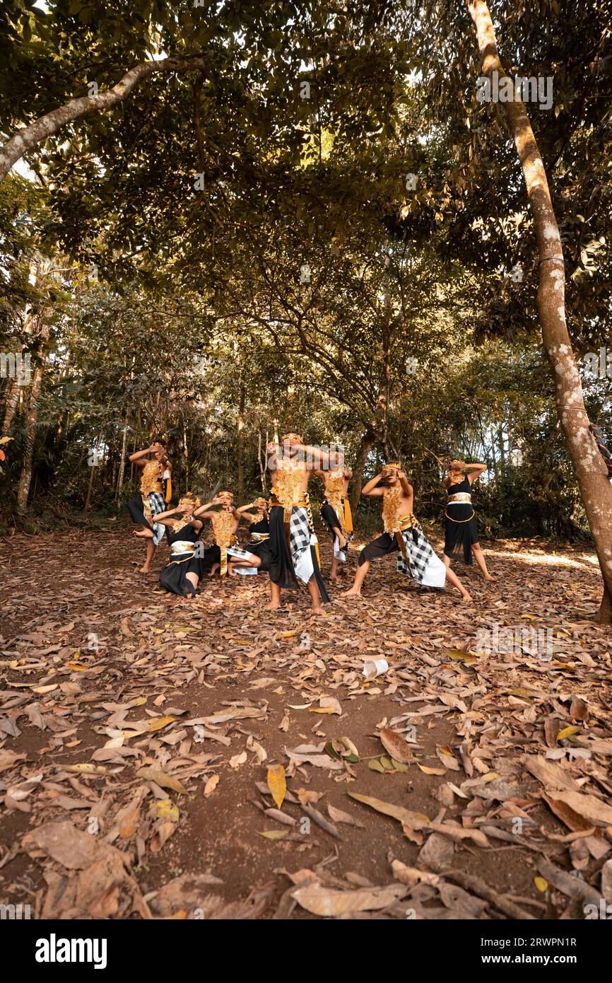 Balinese dancers with golden costumes and stripped pants dance together ...