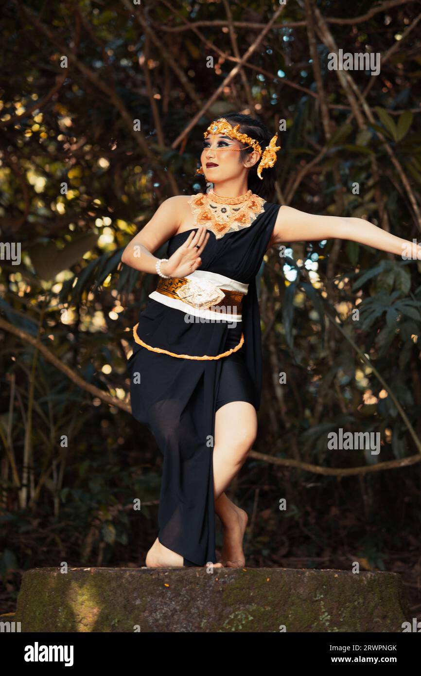 Balinese woman dancing on the top of the rock while wearing a black ...