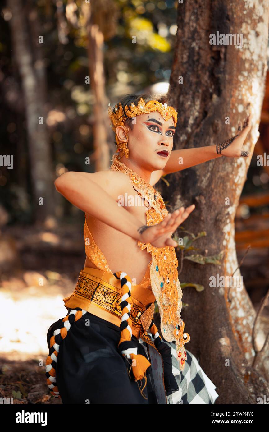 Balinese dancers dance inside the forest while wearing golden crowns ...