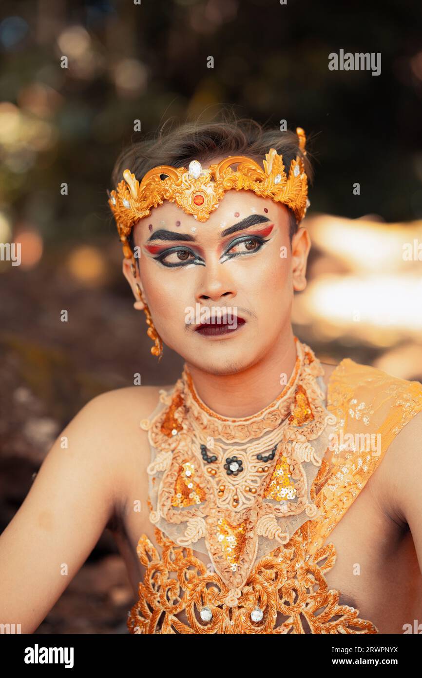 Balinese man with eyeshadow and black lipstick on his face while ...