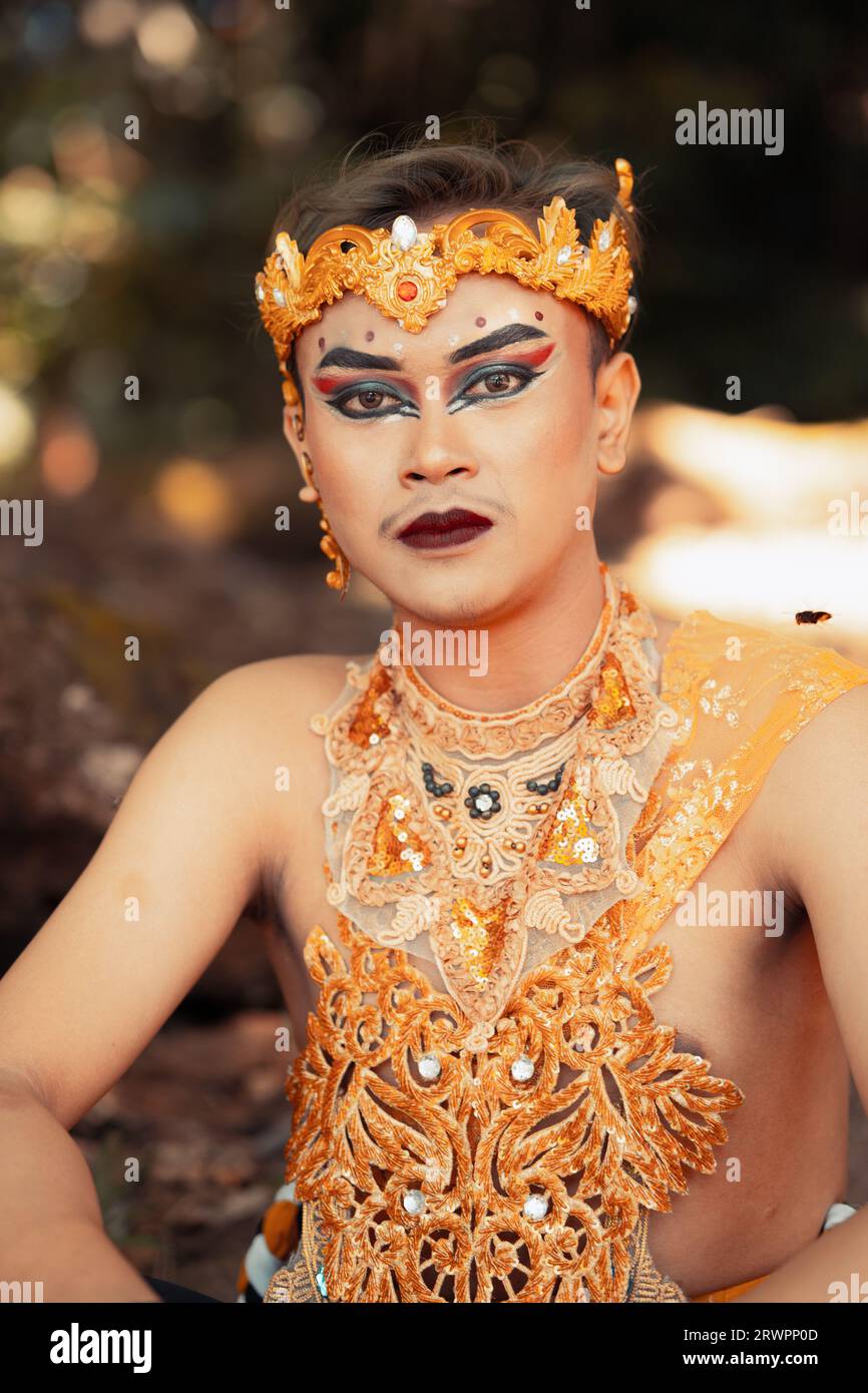 Balinese man with eyeshadow and black lipstick on his face while ...