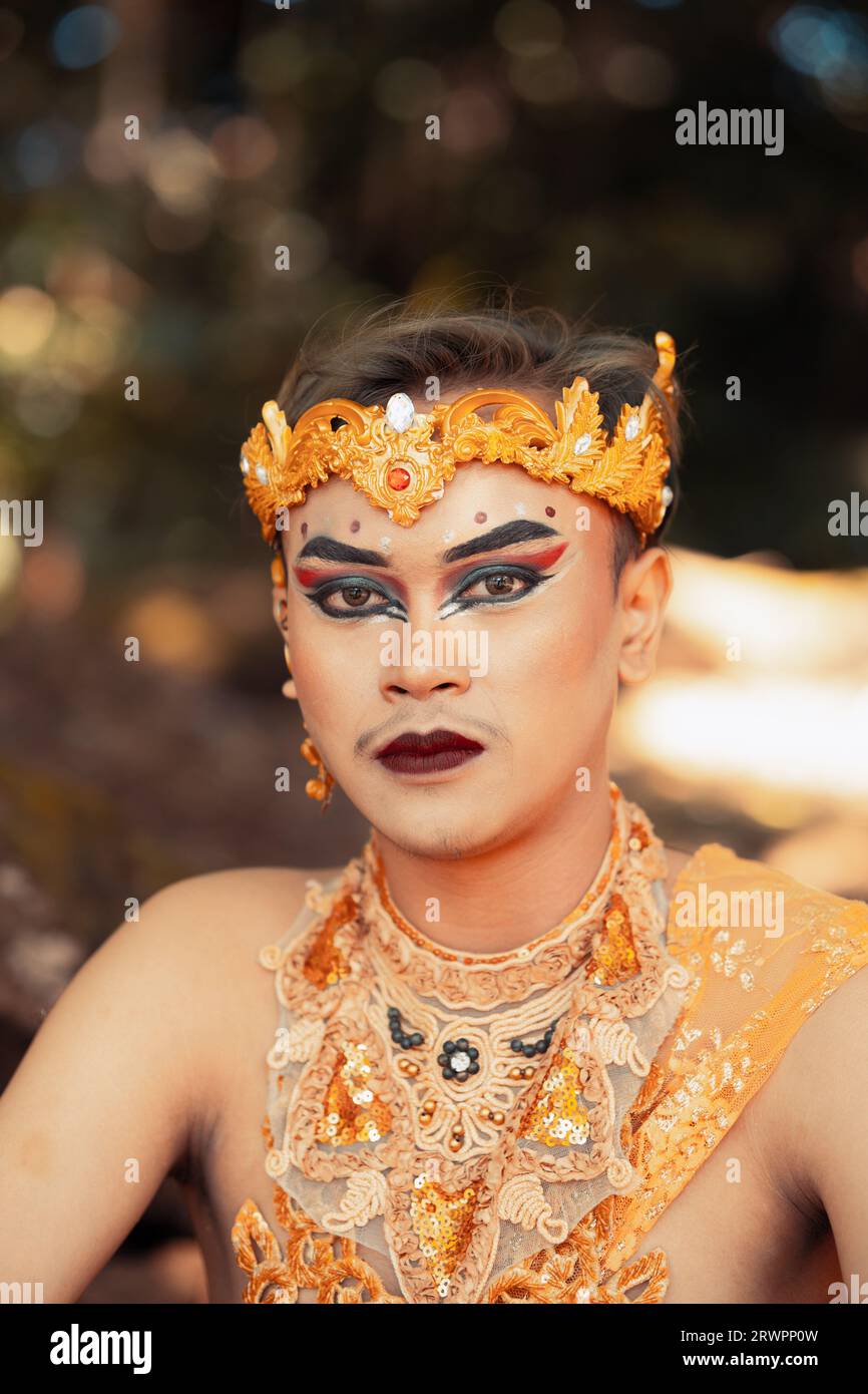 Balinese man with eyeshadow and black lipstick on his face while ...