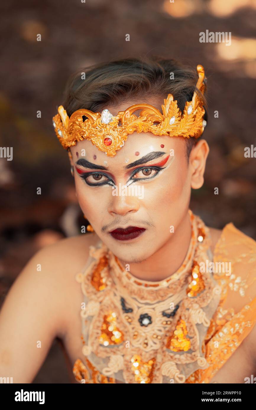 Balinese man with eyeshadow and black lipstick on his face while ...