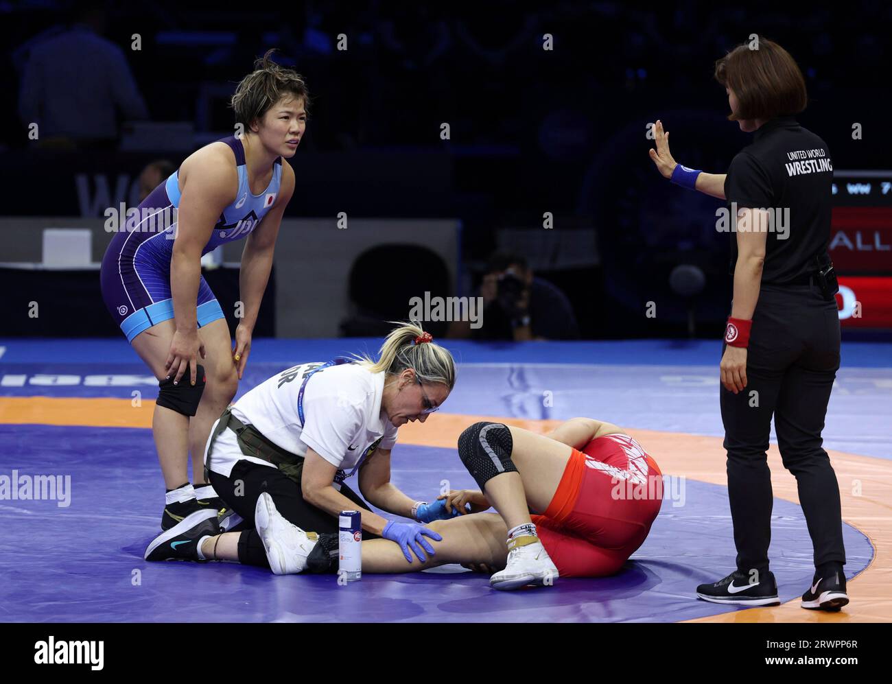 Yuka Kagami of Japan (blue) cares Aiperi Medet Kyzy of Kyrgyzstan ...