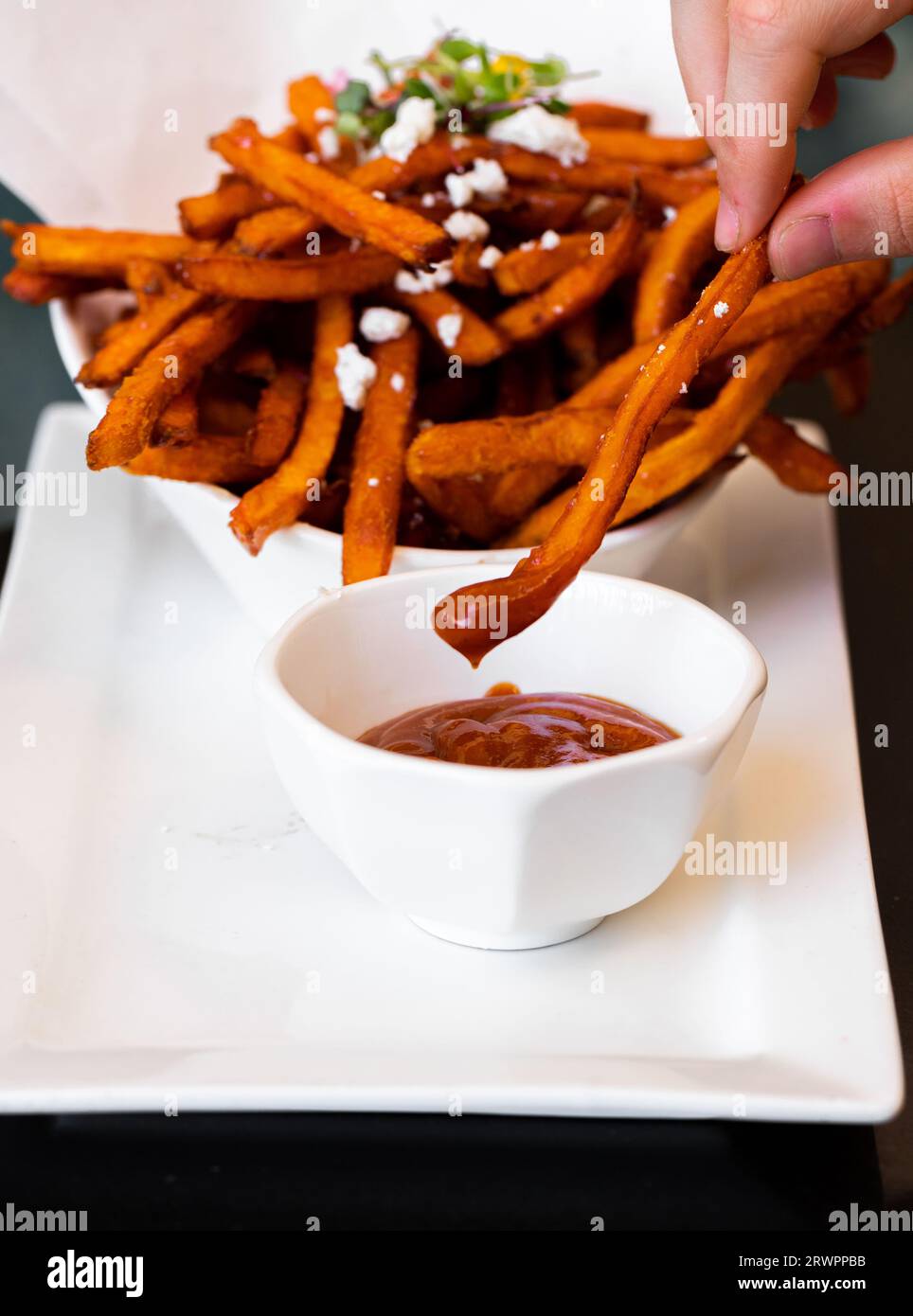 Sweet potato fry dipped in ketchup Stock Photo - Alamy